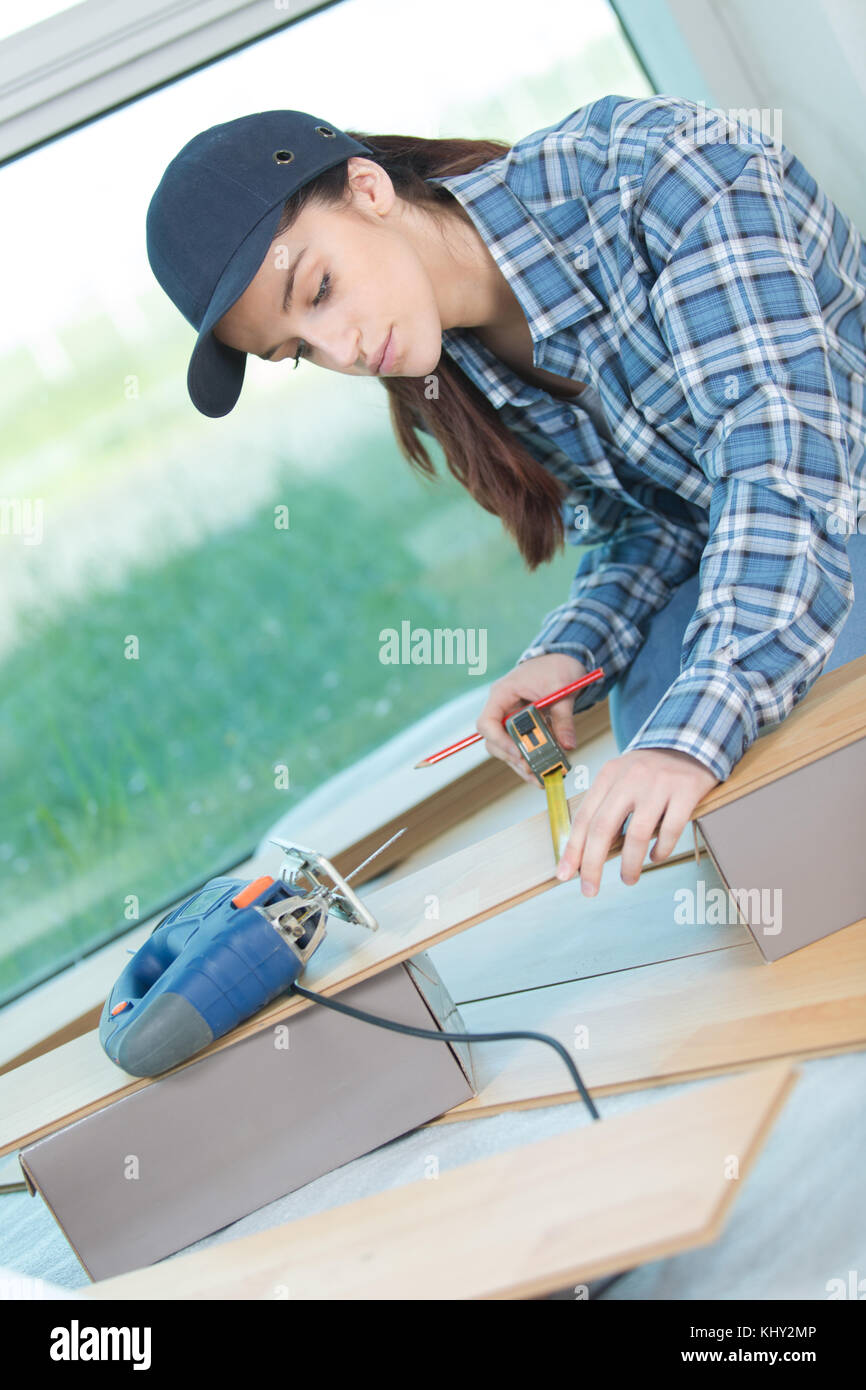 female carpenter measuring suitable wood board in workshop Stock Photo ...