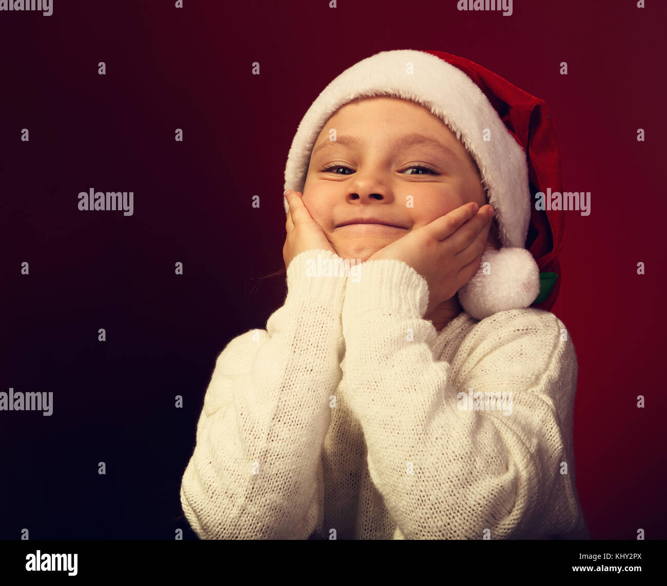 Cute happy smiling girl in fur santa claus hat looking up and thinking ...