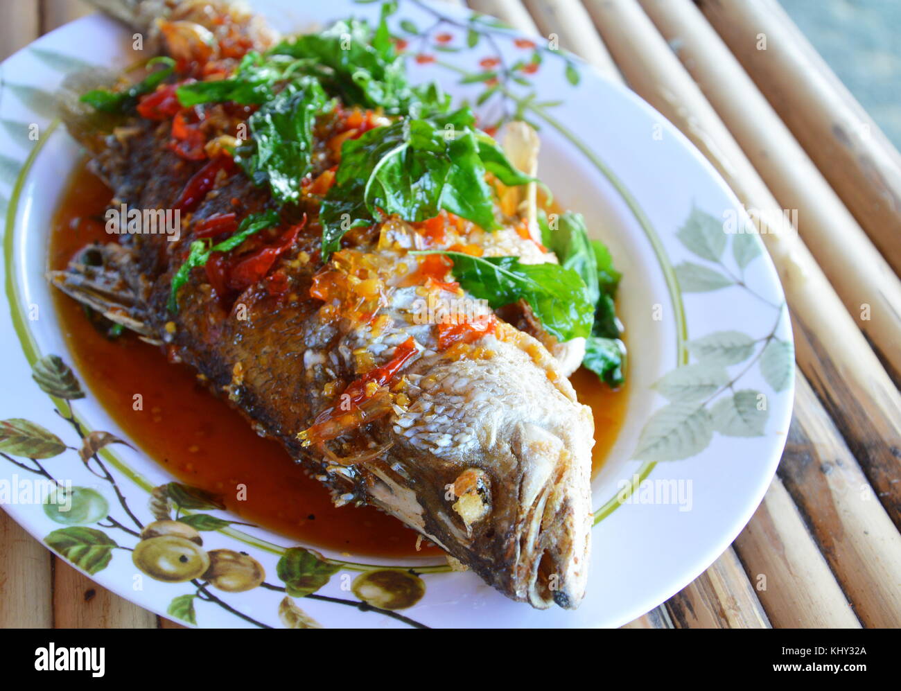 fried bass fish dressing with chili sauce on plate Stock Photo - Alamy