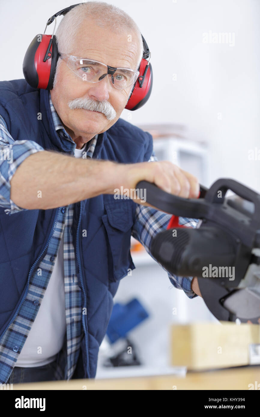 senior man wearing ear protectors while using circular saw Stock Photo ...