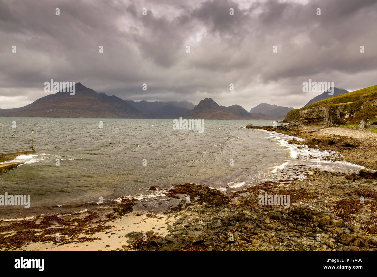 Brooding clouds and dark skies hang over the Black Cuillin hills viewed ...