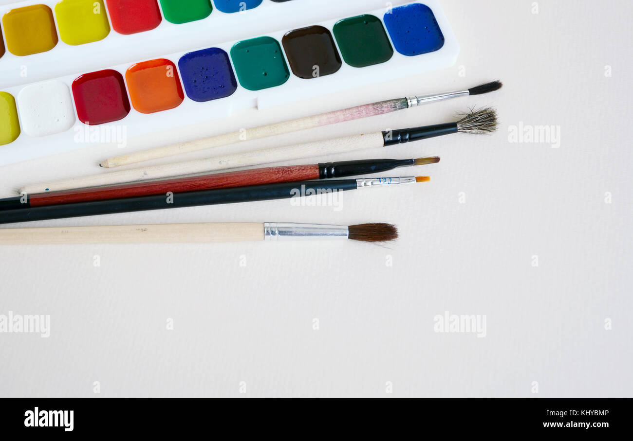 Paint brushes and a set of paints on a white paper Stock Photo - Alamy