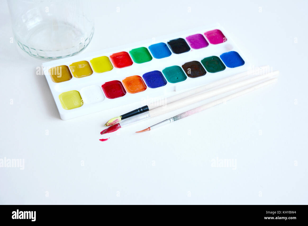 Paint brushes and a set of paints on a white paper Stock Photo - Alamy