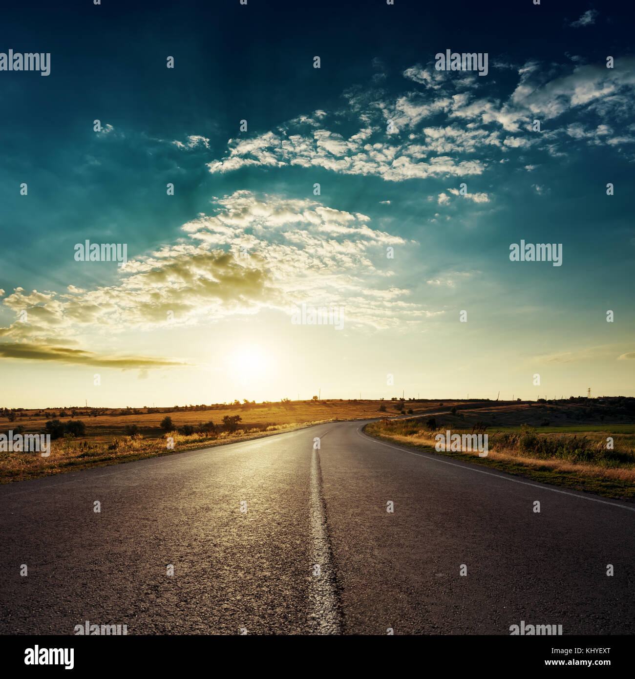 low sun in dramatic clouds over asphalt road, sunset time Stock Photo - Alamy