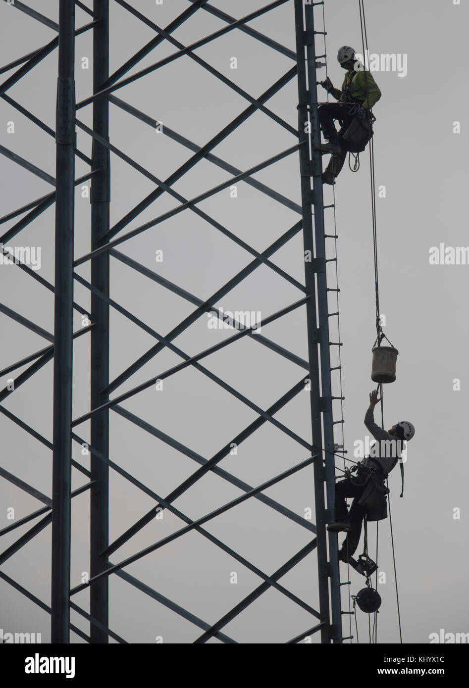 Two technicians work on a high voltage line high above the ground near ...