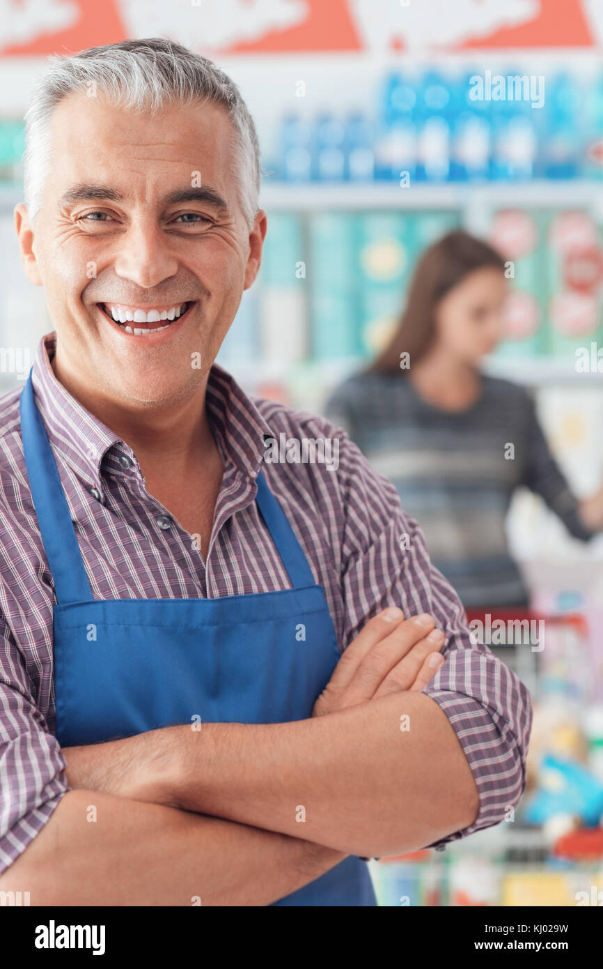 Confident smiling supermarket clerk posing at the shopping mall, retail ...