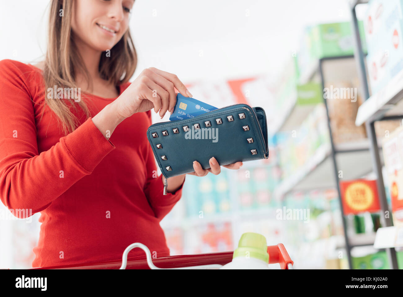 Woman at the supermarket checkout, she is taking a credit card from her ...