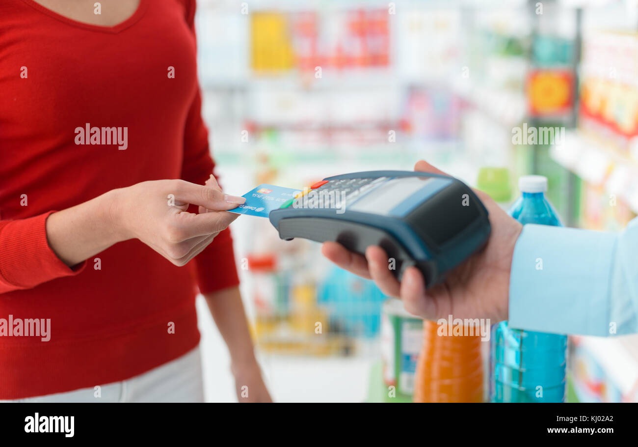 Woman at the supermarket checkout, she is inserting her credit card in ...