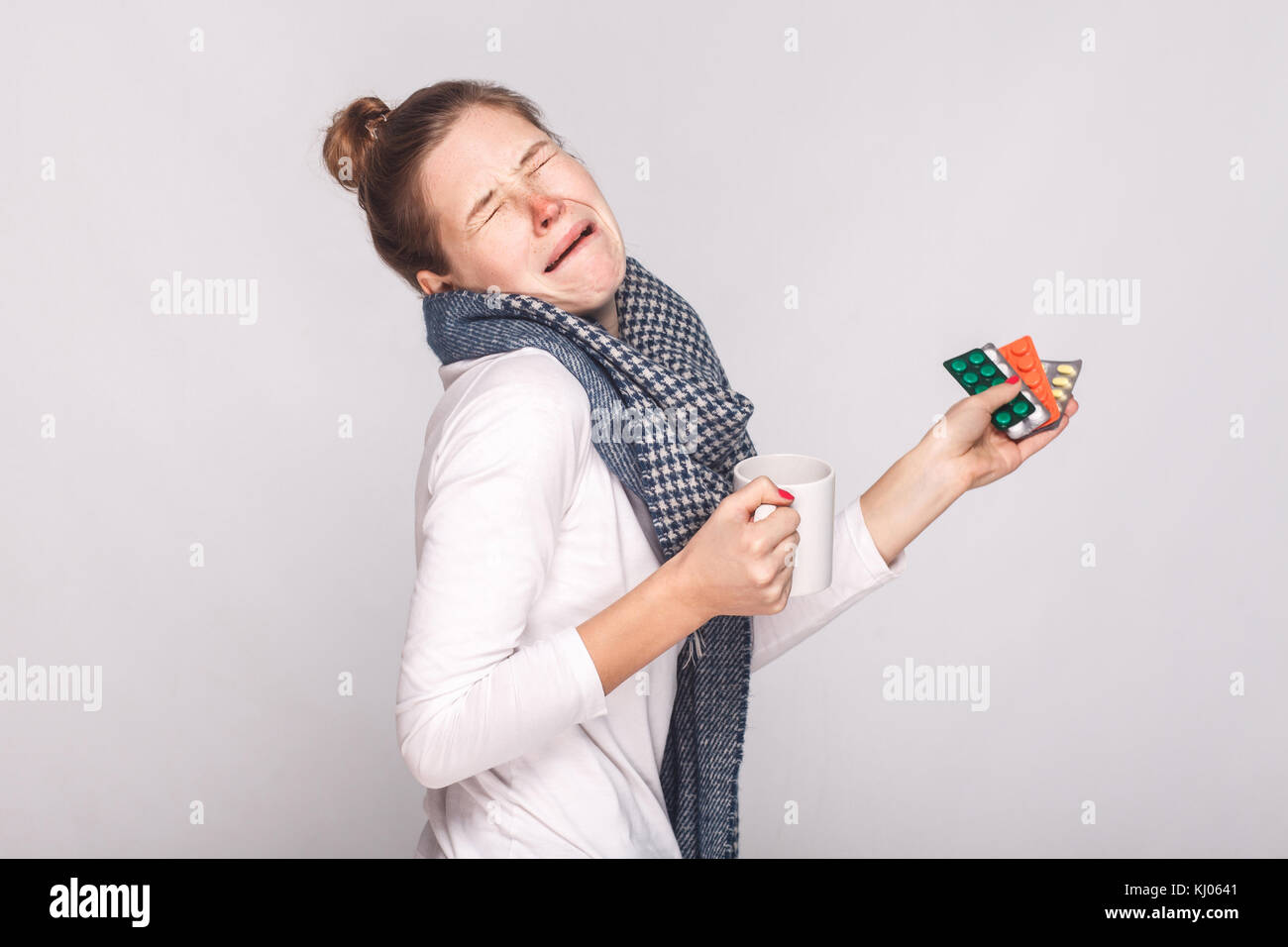 Woman cry because she was sick. Holding cup with tea, many pills and ...