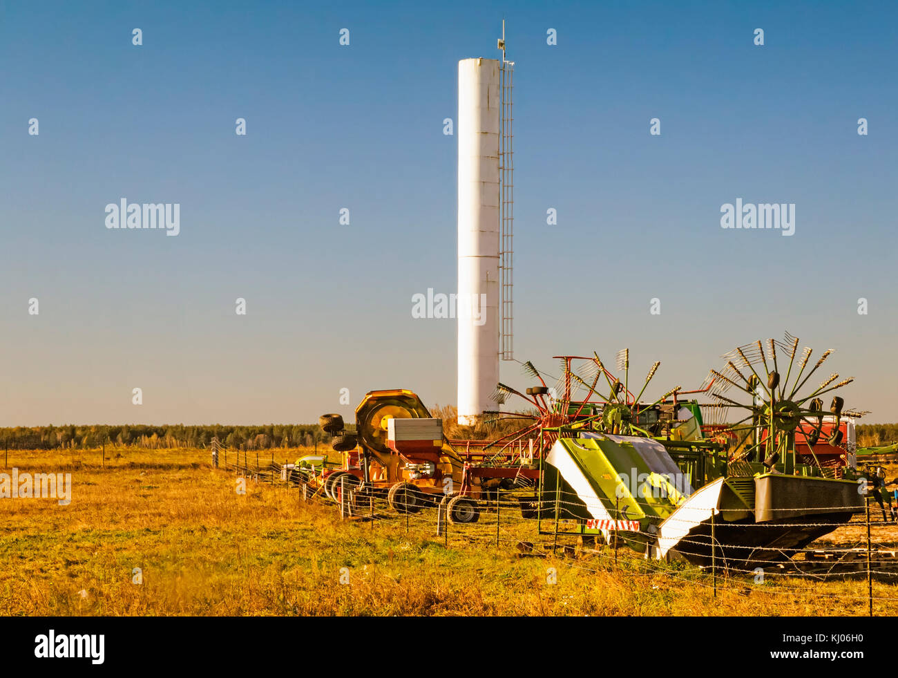 In the field next to a high tower are agricultural machines for the ...
