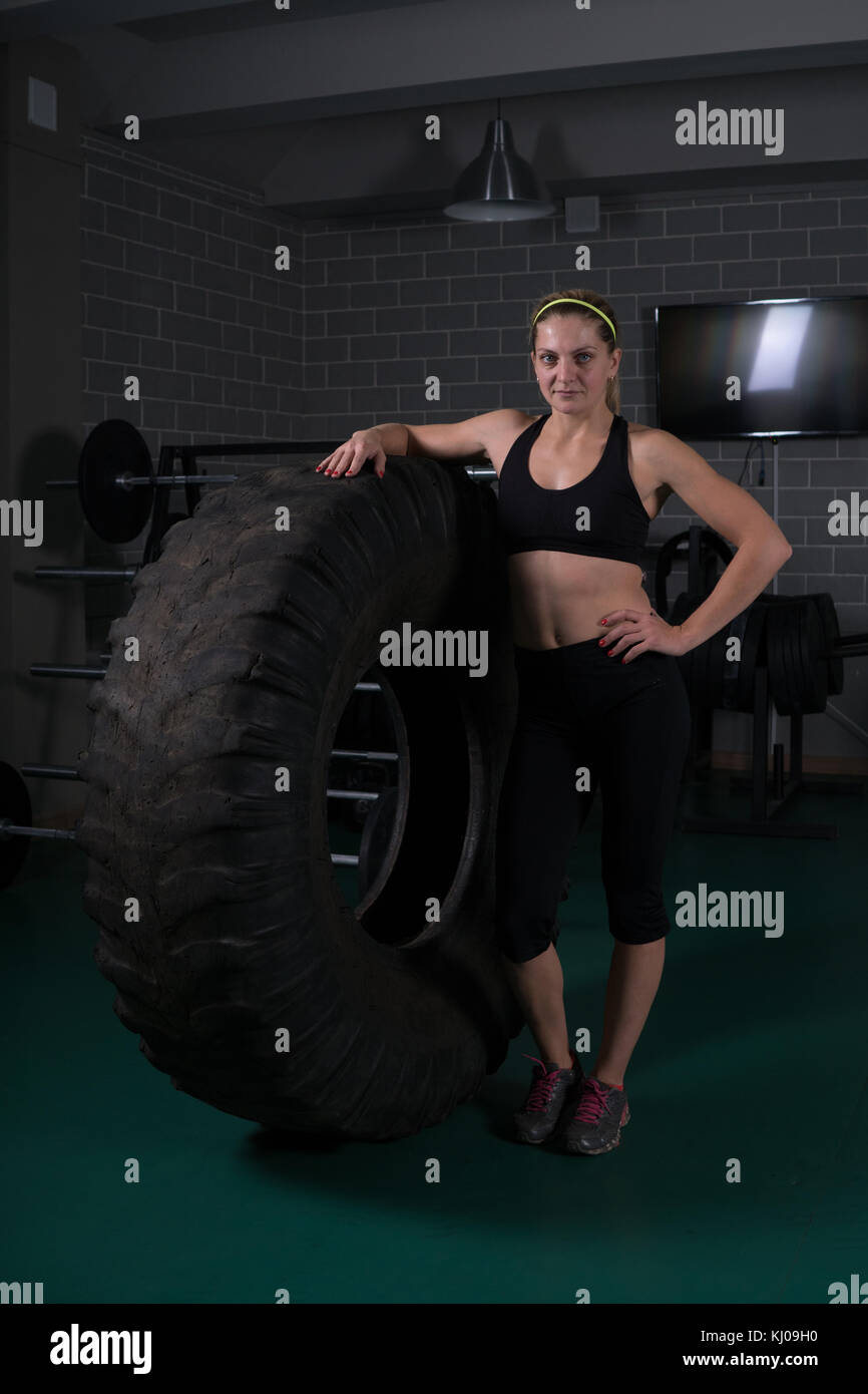 Woman bodybuilding. Fitness woman posing near the tire in the gym Stock ...