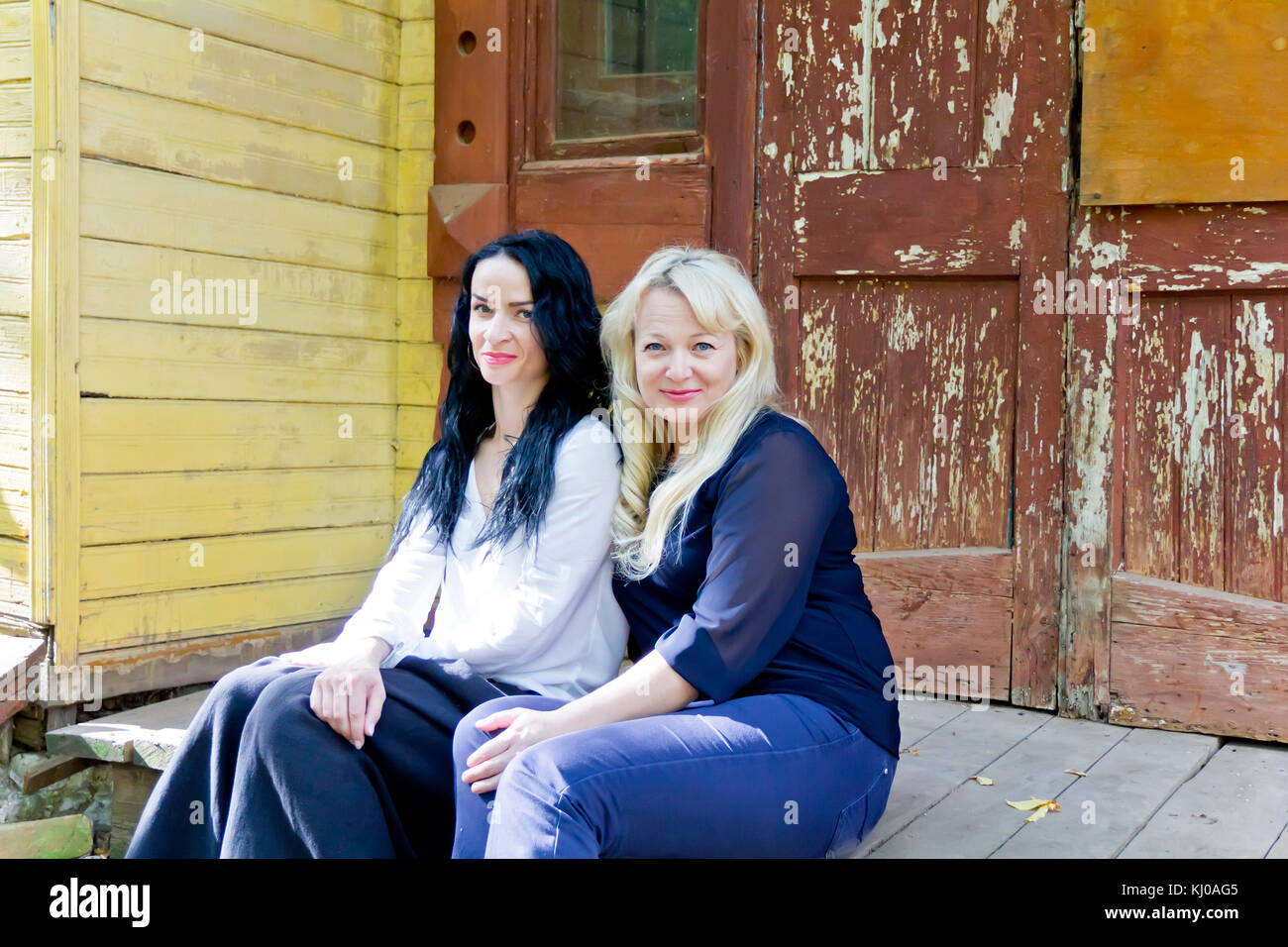 Two women are sitting on wooden porch Stock Photo - Alamy