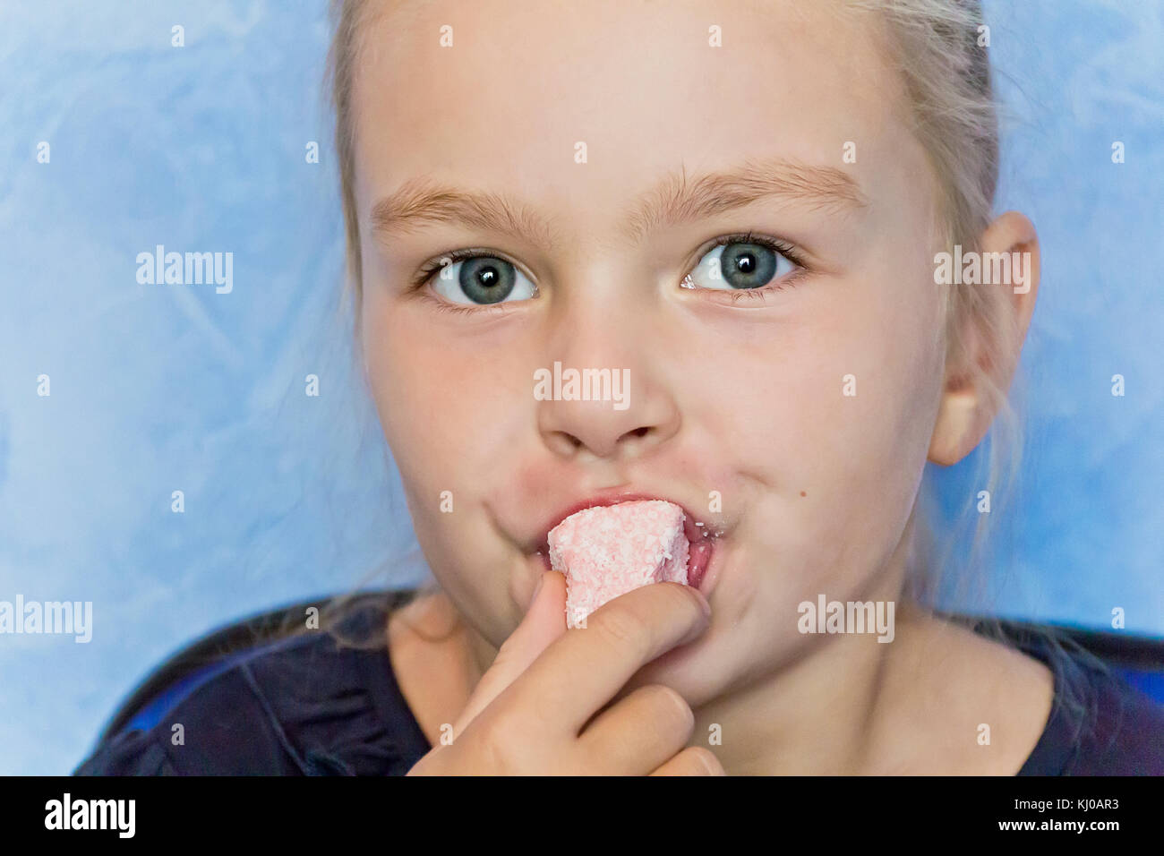 Cute eating girl with blond hair on blue background Stock Photo - Alamy