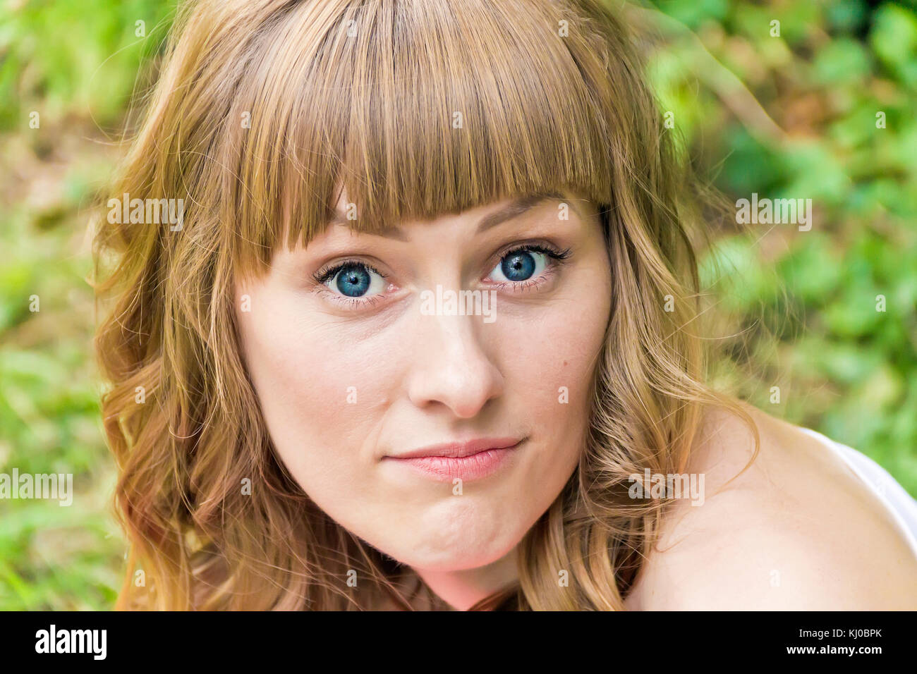 Horizontal portrait of young woman with big bulging blue eyes on summer ...