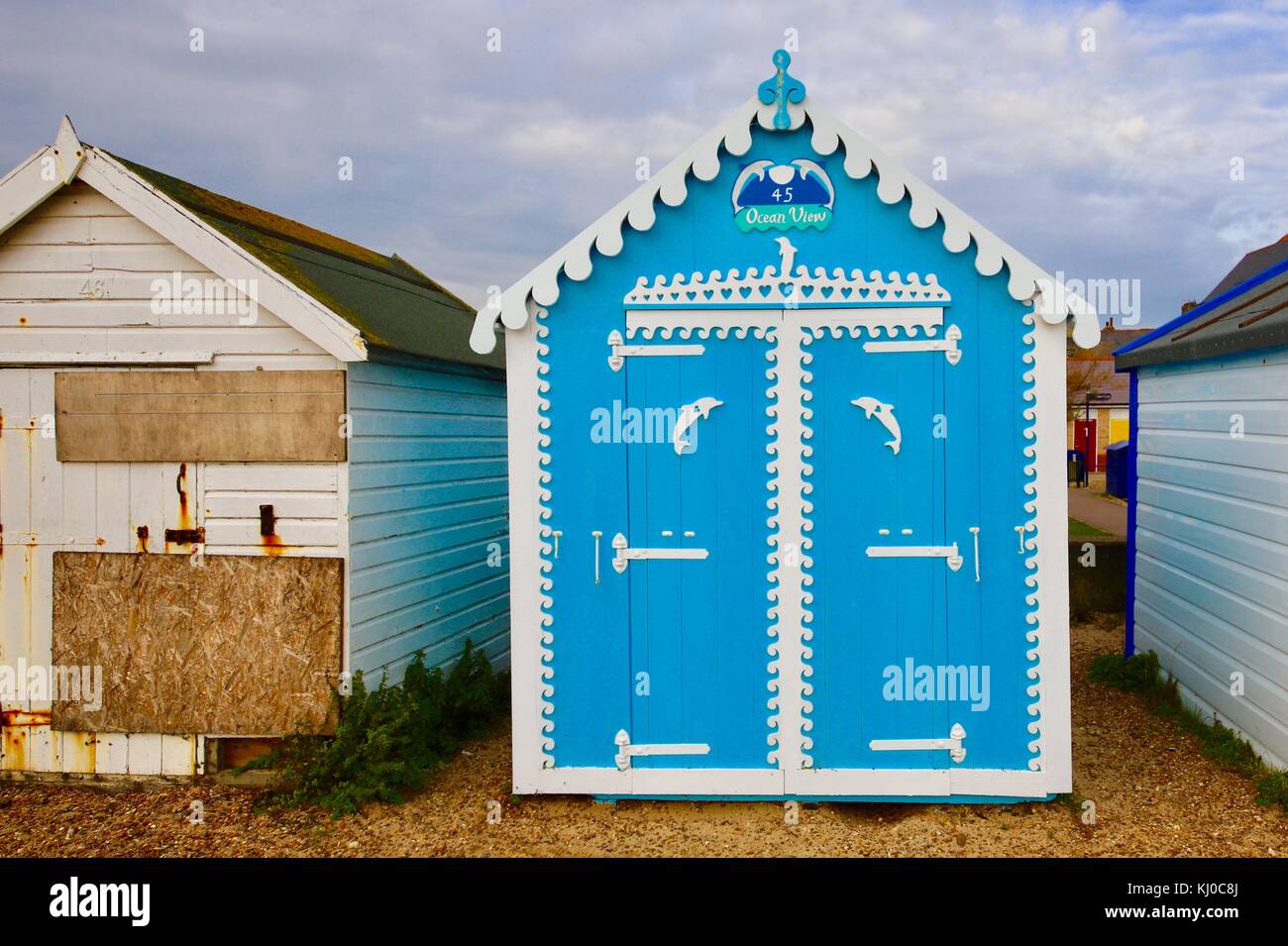 Contrasting beach huts at Felixstowe, Suffolk. One smartly painted blue ...