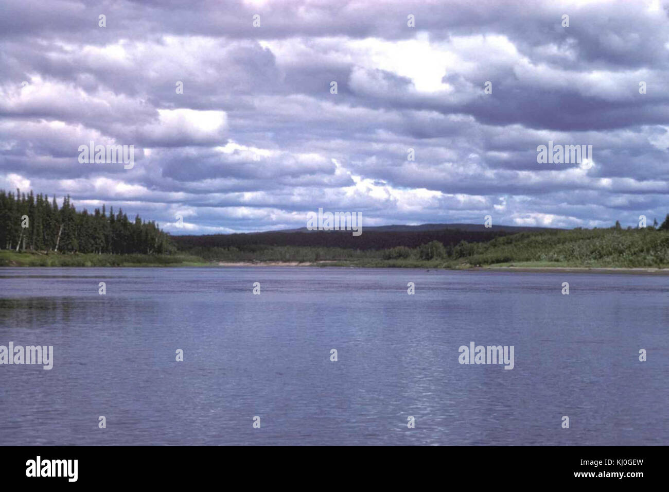 An atmospheric photograph or painting showing gray clouds over a lake ...