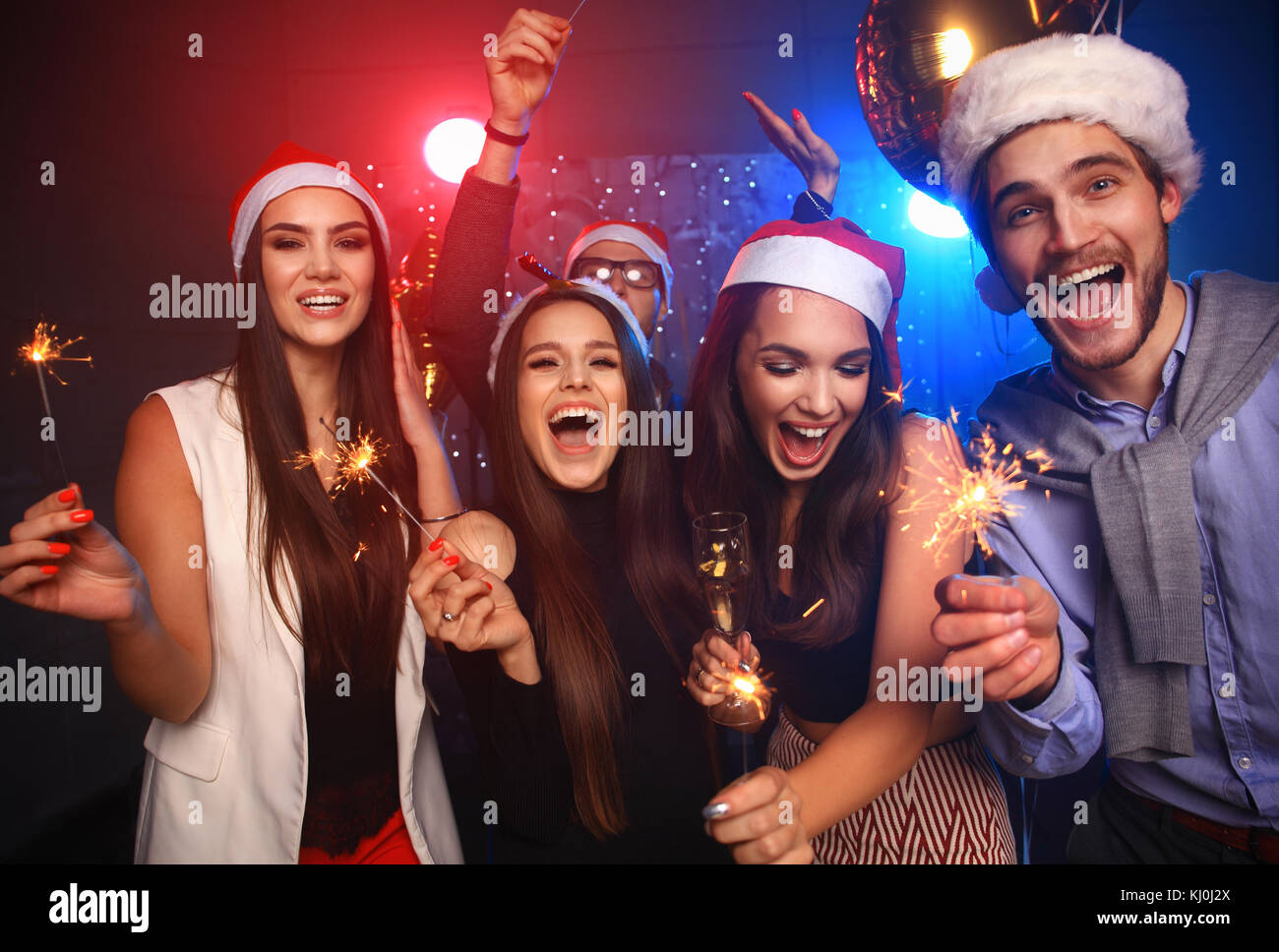 Celebrating New Year together. Group of beautiful young people in Santa ...