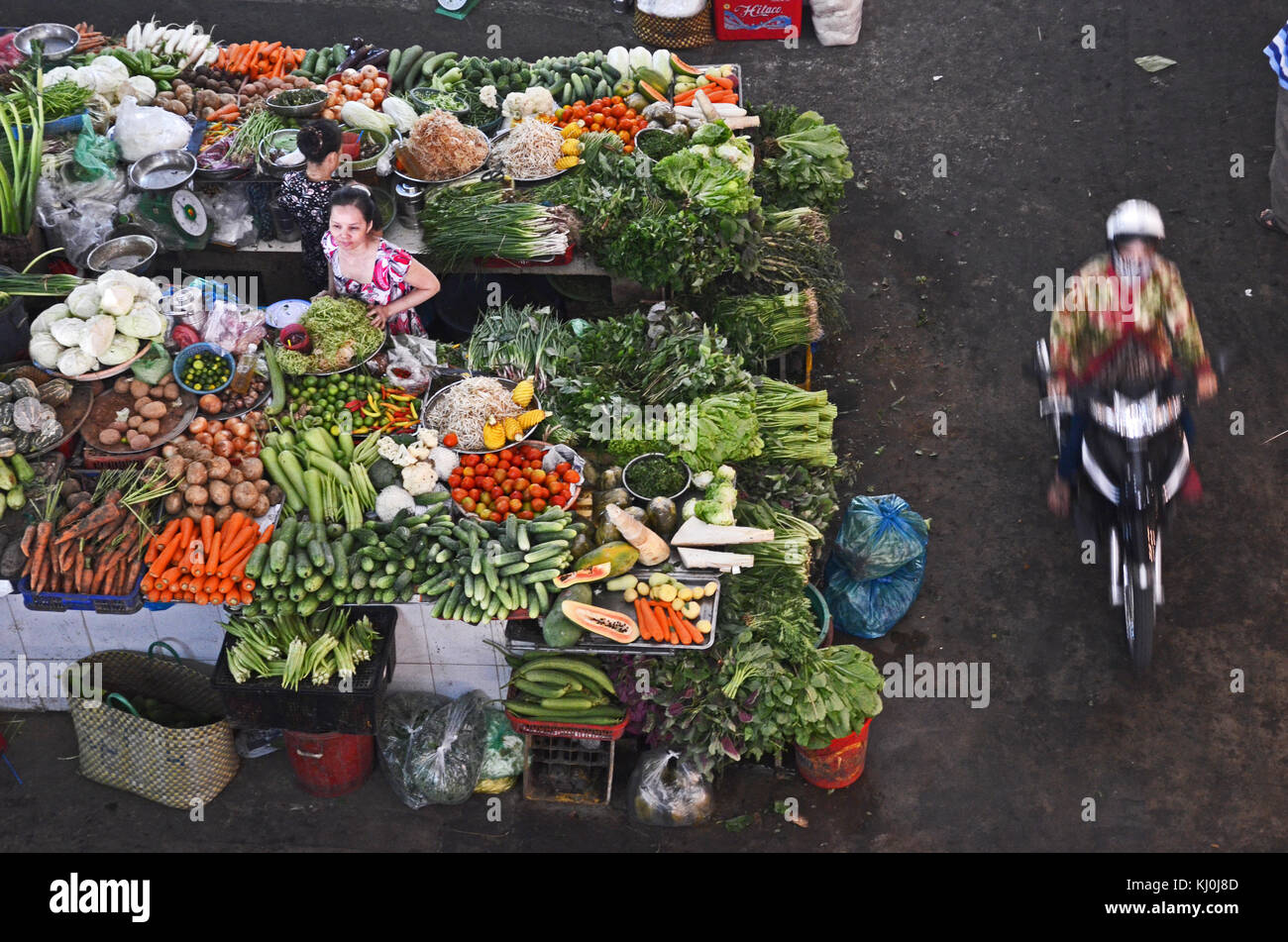 A scooter passes a fruit and vegetable stall in the market in Ben Tre ...
