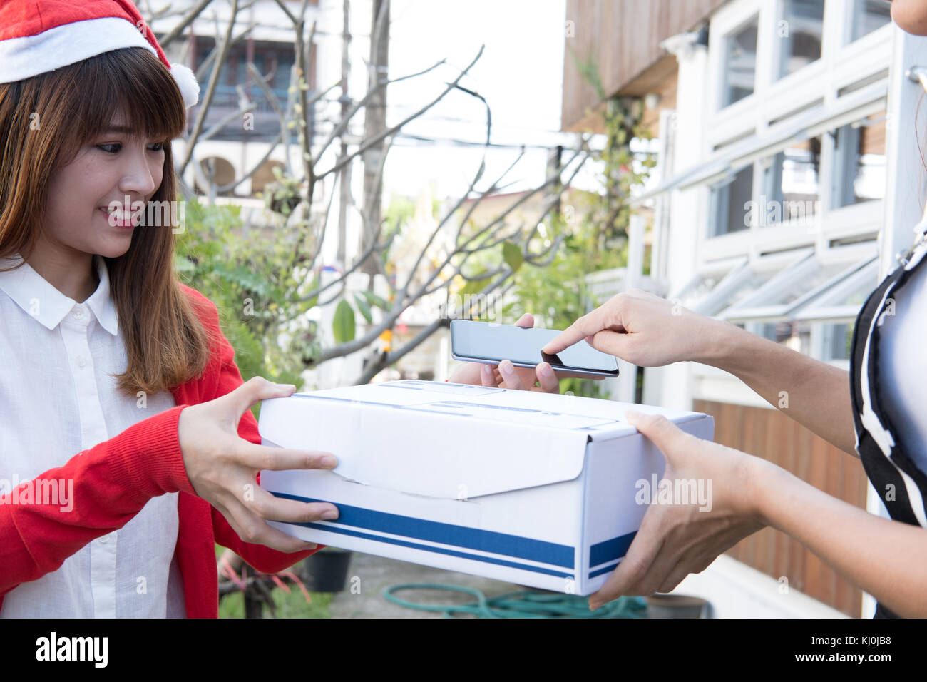 courier wearing santa claus hat delivering a parcel box to customer ...