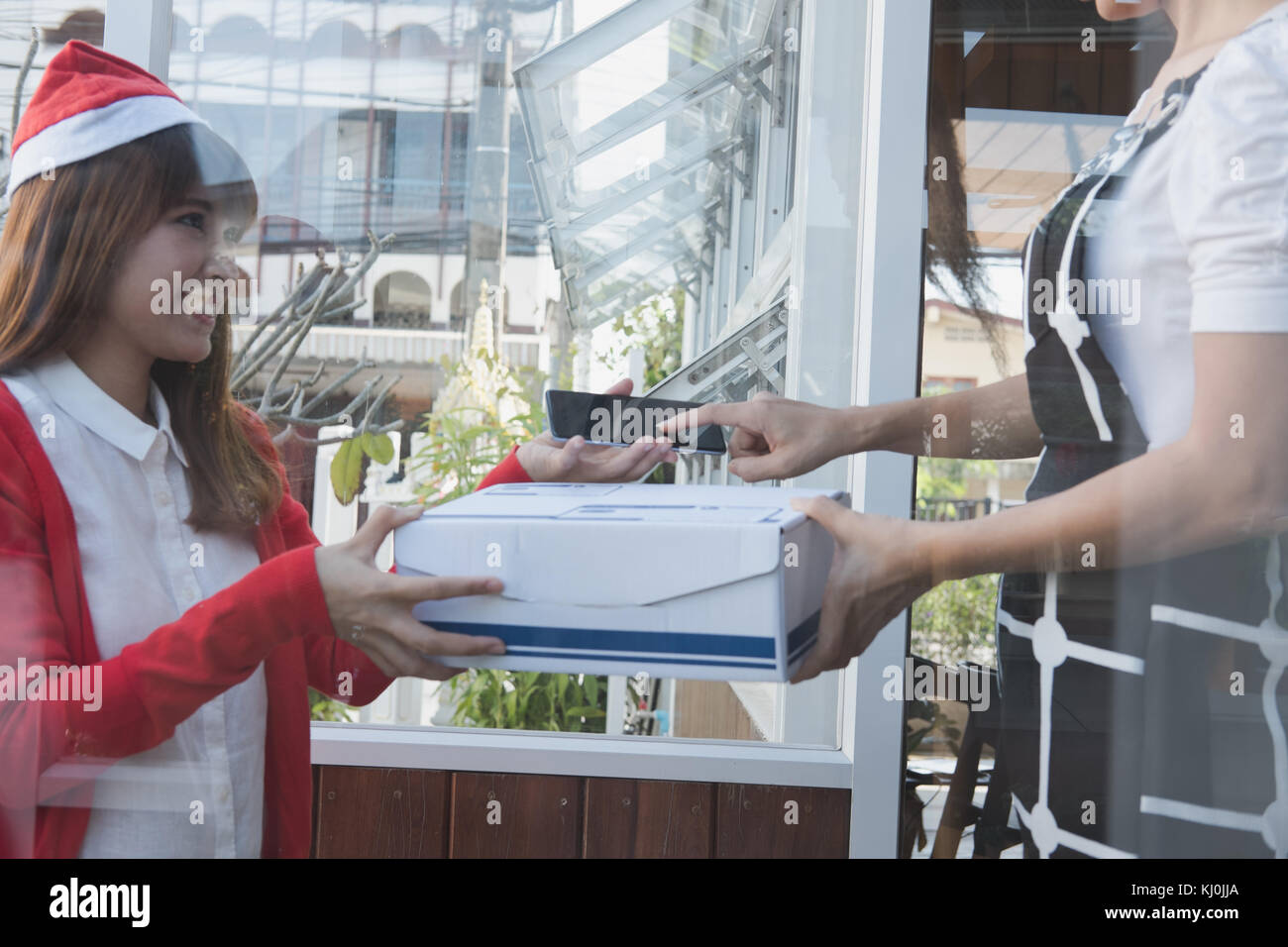 courier wearing santa claus hat delivering a parcel box to customer ...