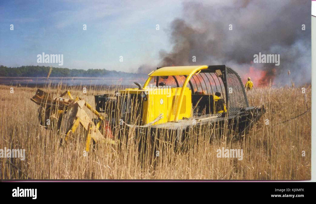 Heavy tracked vehicle in tall grass during prescribed burn Stock Photo ...