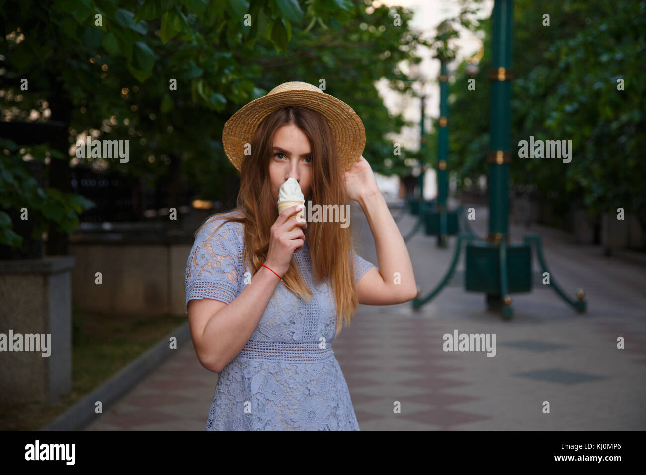 Pretty girl in summer hat is eating ice cream outdoor Stock Photo - Alamy
