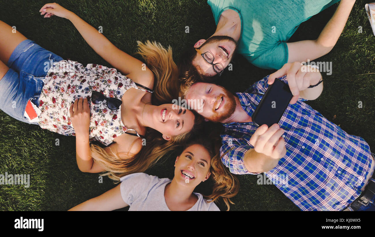 Careless young people having a laugh outdoors lying in grass Stock ...