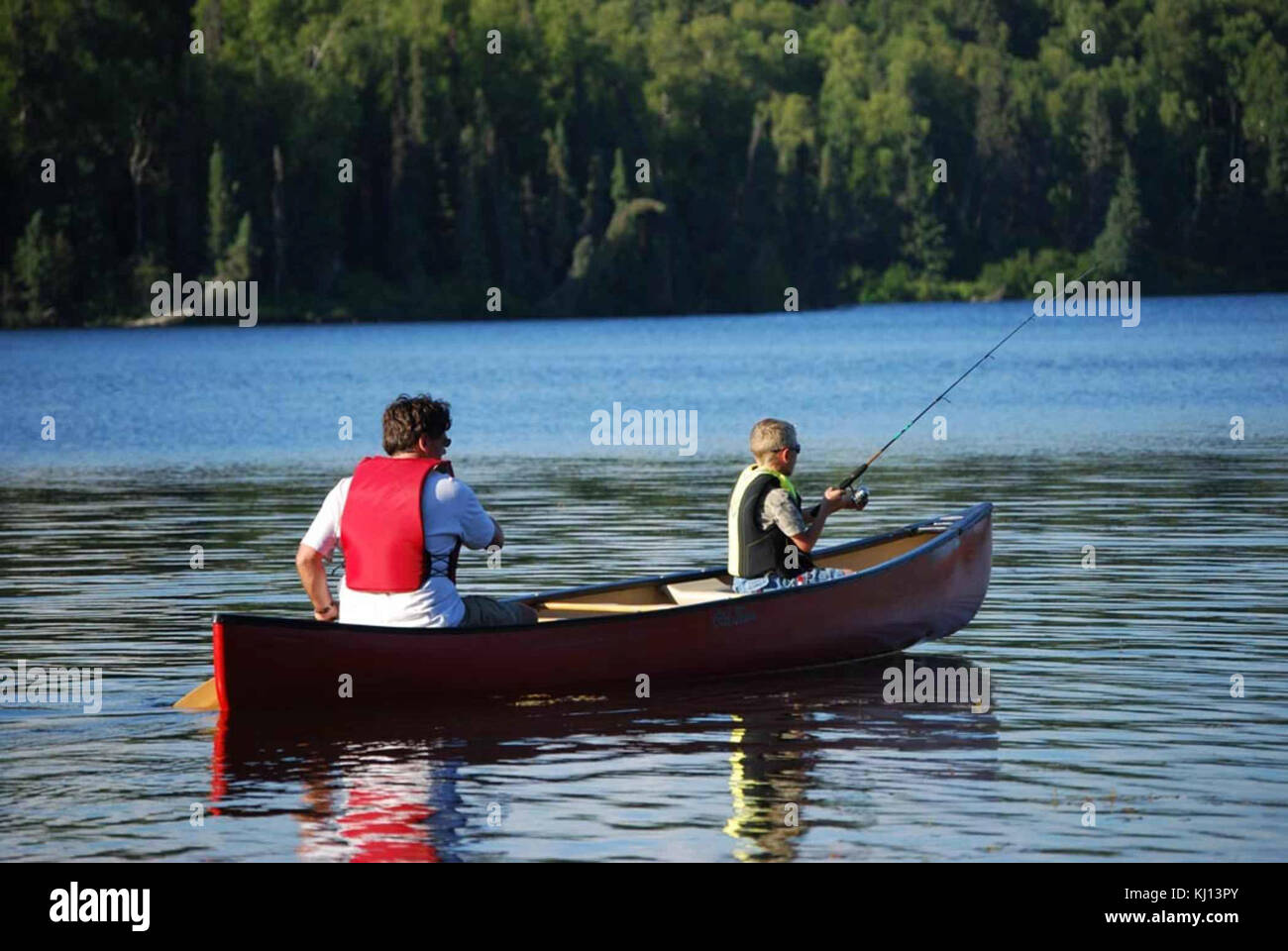 Man and child fish from canoe Stock Photo - Alamy