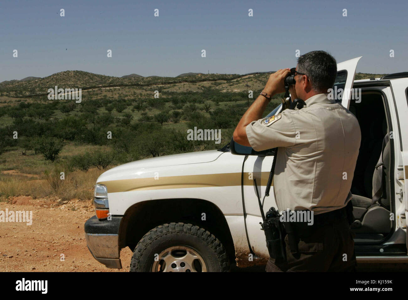 A man patrols an area with a patrol car, observing his surroundings ...