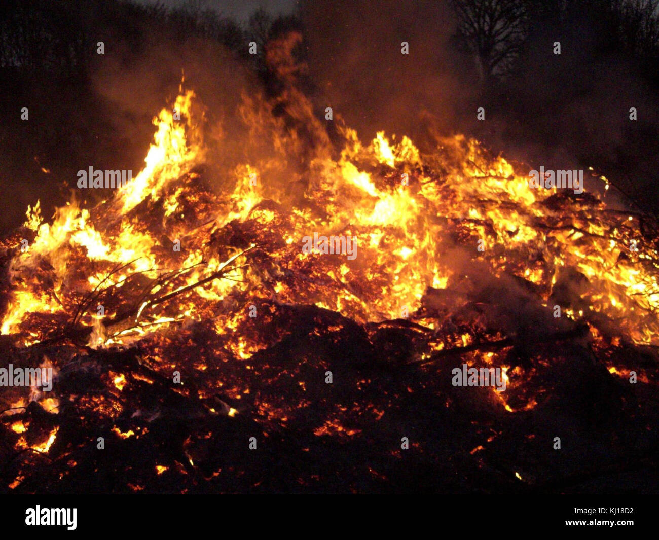 The image depicts a campfire burning in the wilderness, a traditional ...
