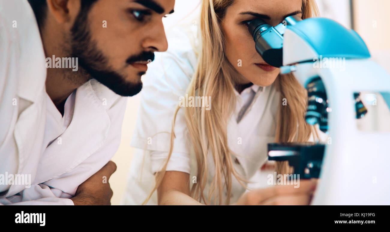 Group of scientists doing research looking through microscope Stock ...
