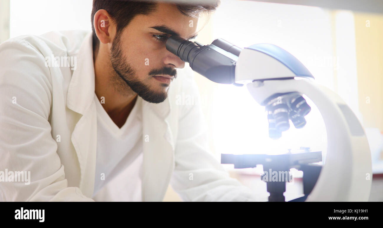 Young scientist looking through microscope in laboratory Stock Photo ...