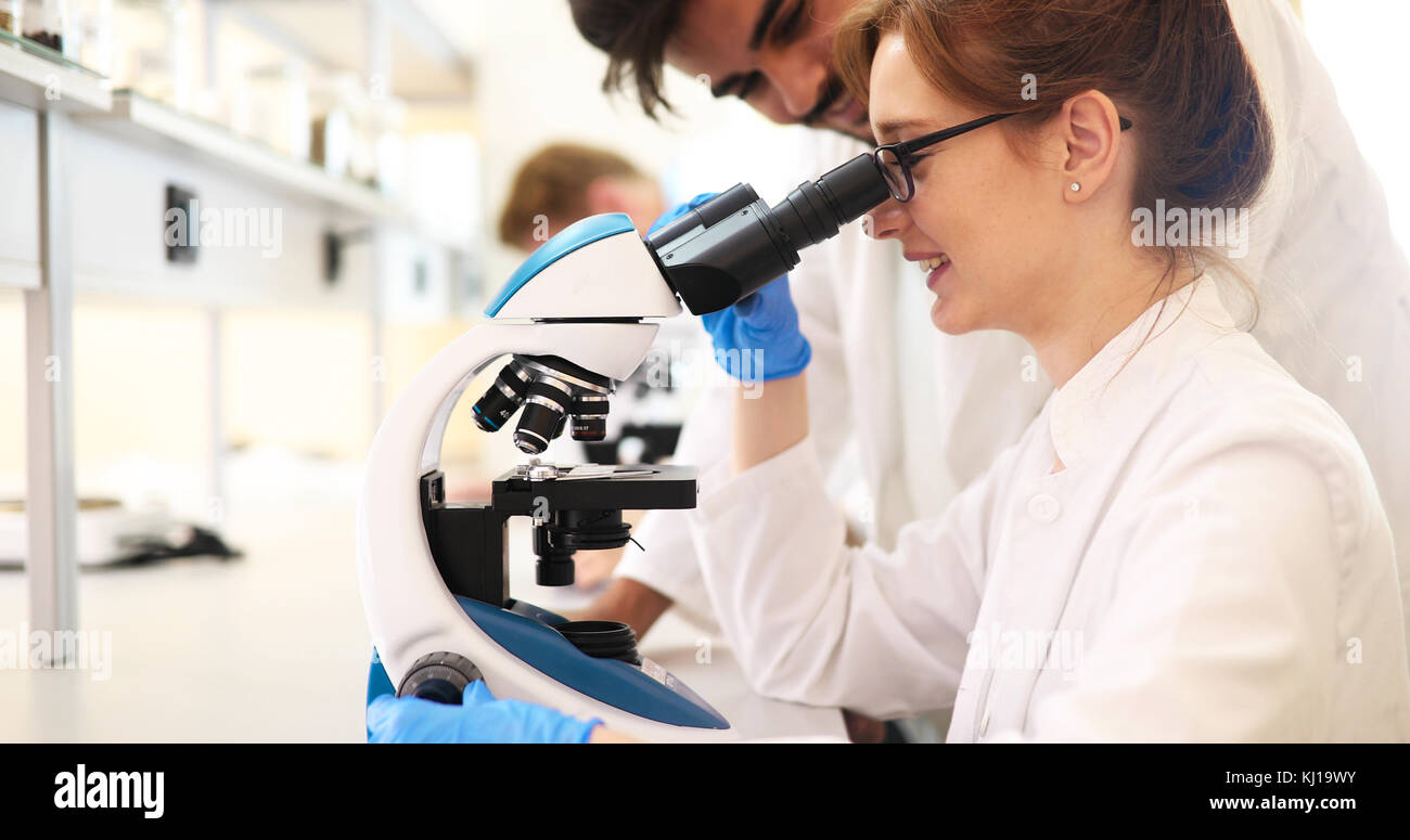 Young scientist looking through microscope in laboratory Stock Photo ...