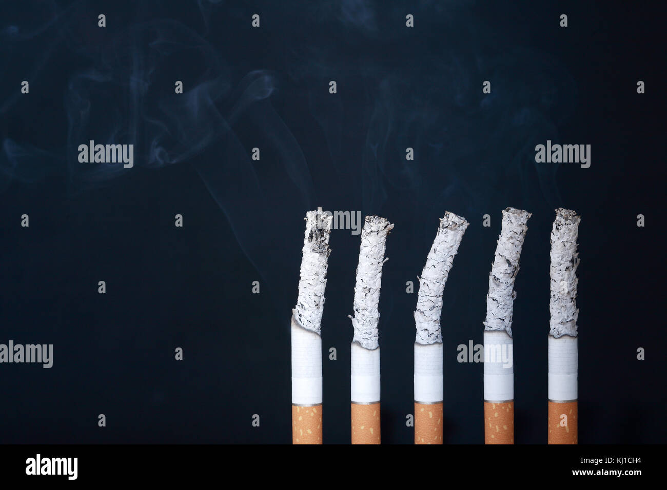 Five cigarettes with smoke and ashes on dark background Stock Photo - Alamy