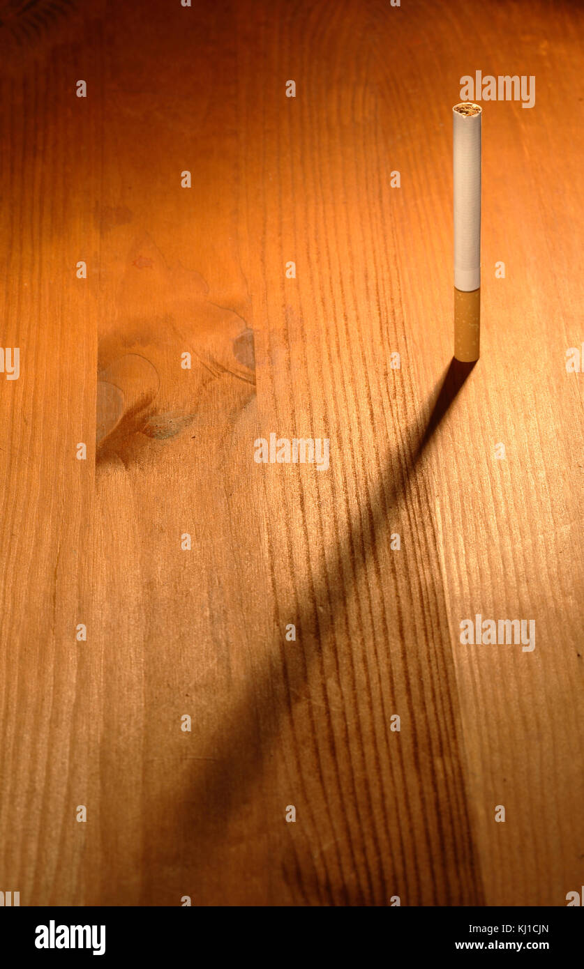 One cigarette standing on wooden background with long shadow Stock ...