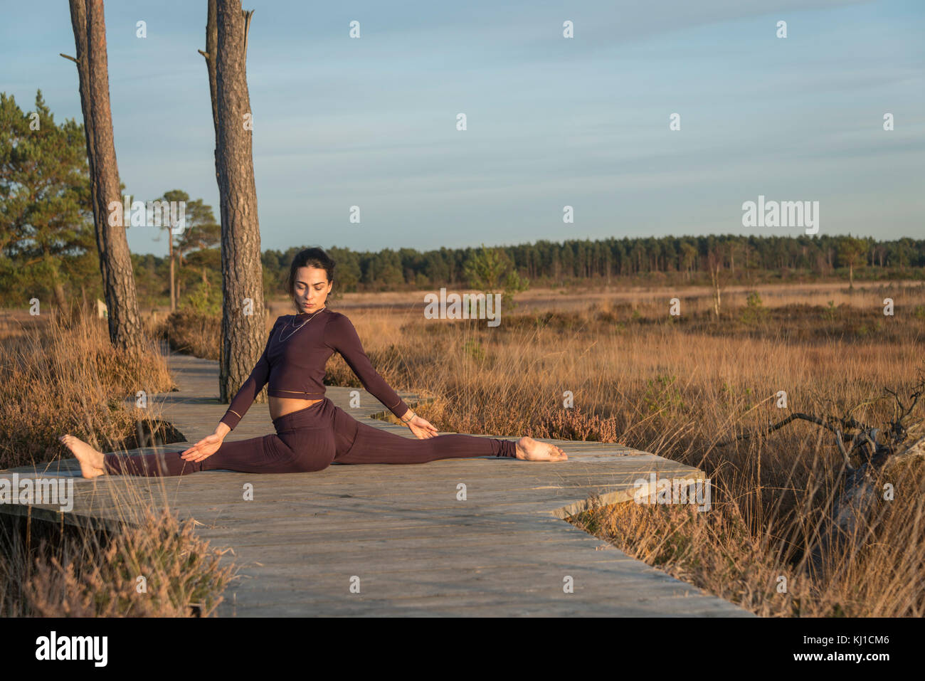 woman practicing yoga outside in open space in a nature reserve, doing ...