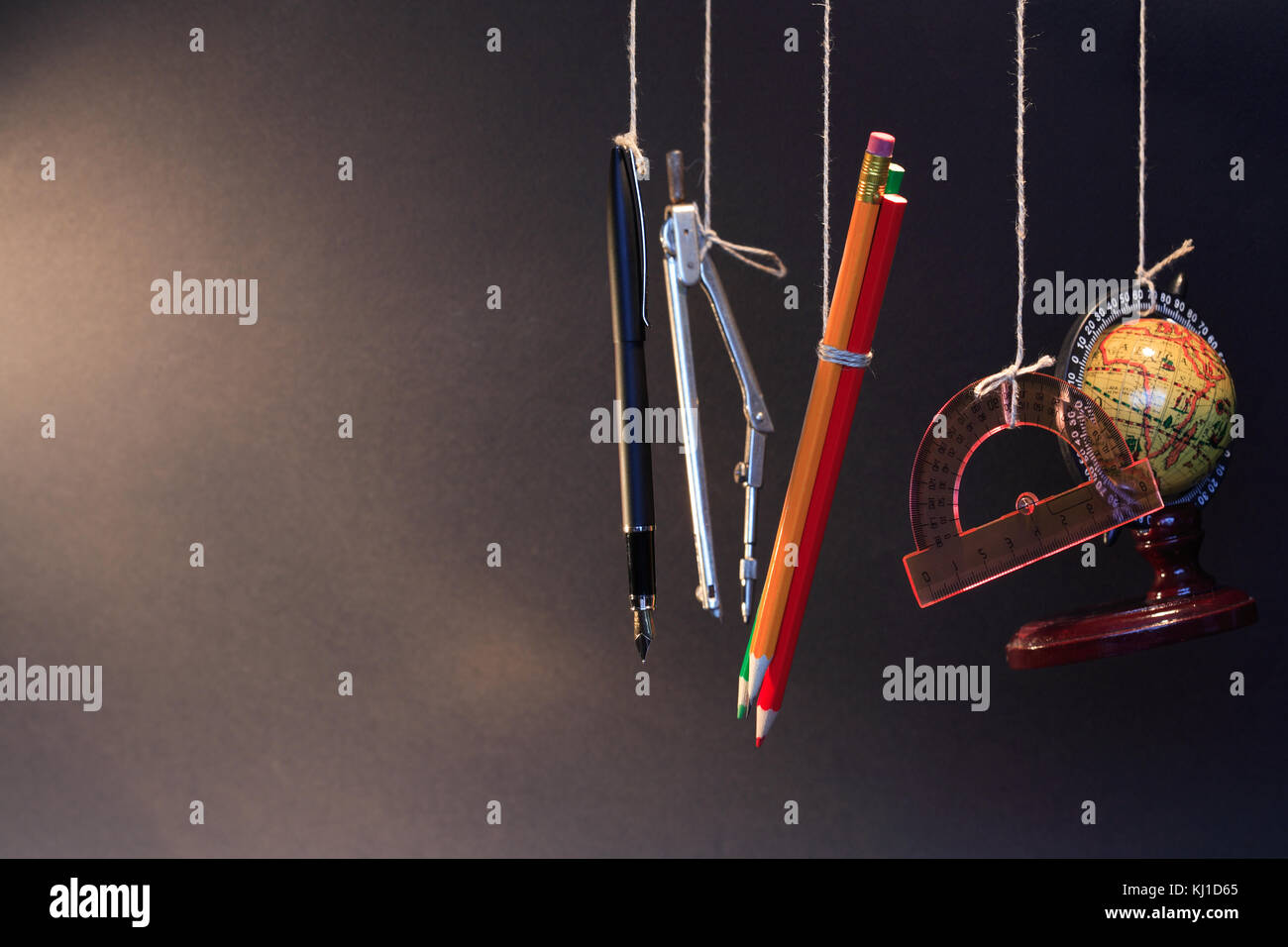 Color pencils, fountain pen and other objects hanging with ropes on ...