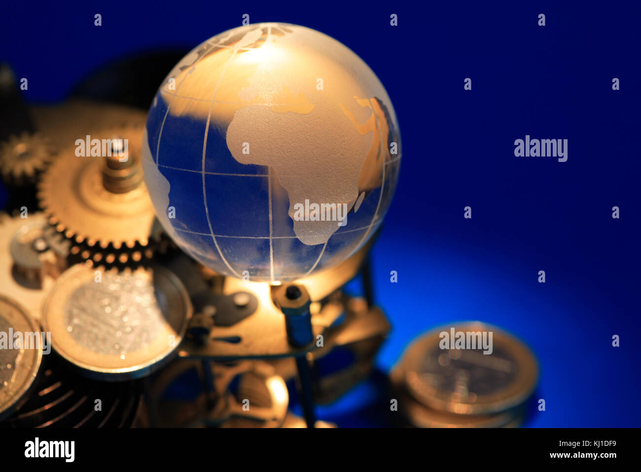 Glass globe lying on gears and coins on dark blue background Stock ...