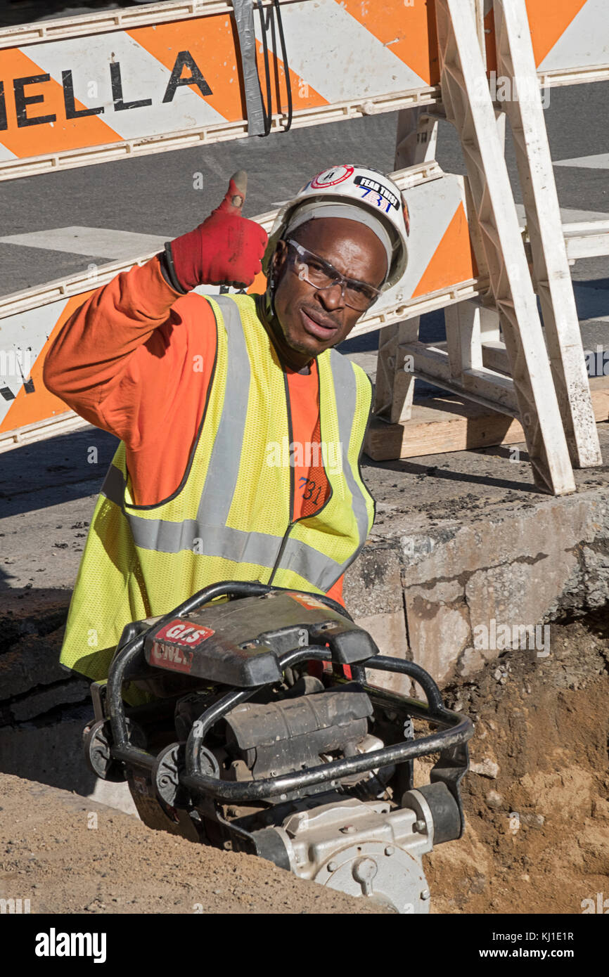 A construction worker working on underground piping using a compactor ...