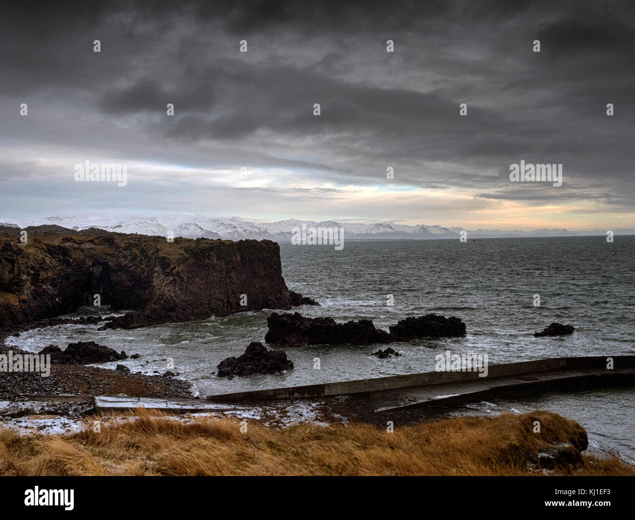 View across the bay from Hellnar towards the snow covered mountains of ...