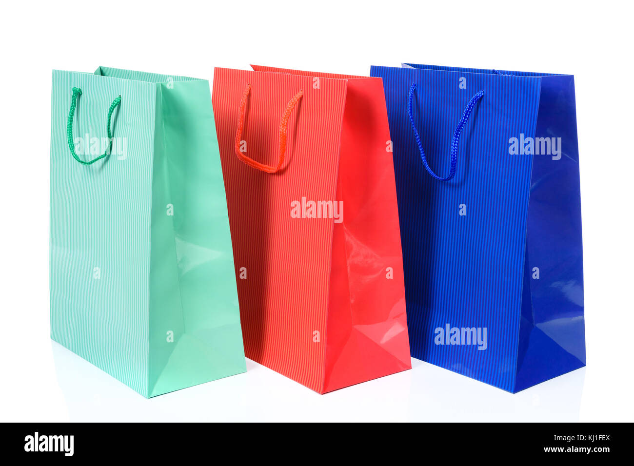 Three shopping bags in different colors in close up and isolated on a ...