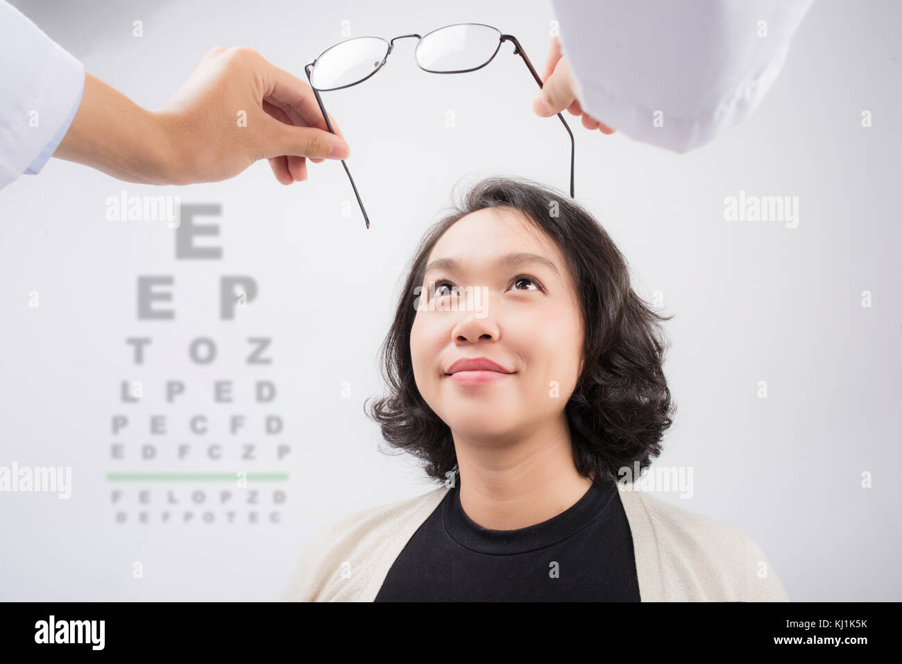 New glasses. Optometrist giving asian woman eyeglasses to try Stock ...