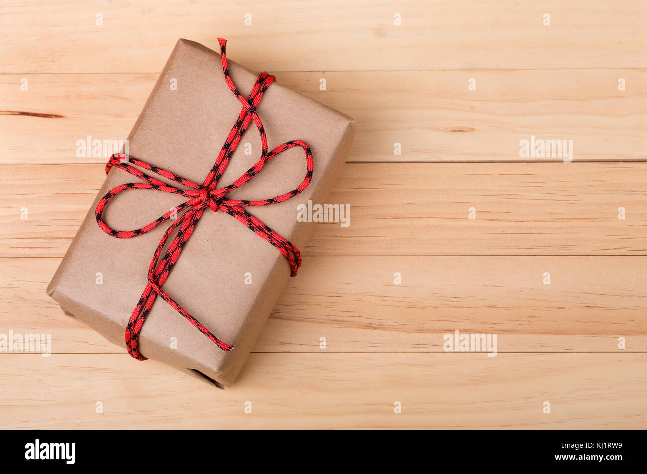 Brown package tied with red string on wood background Stock Photo - Alamy