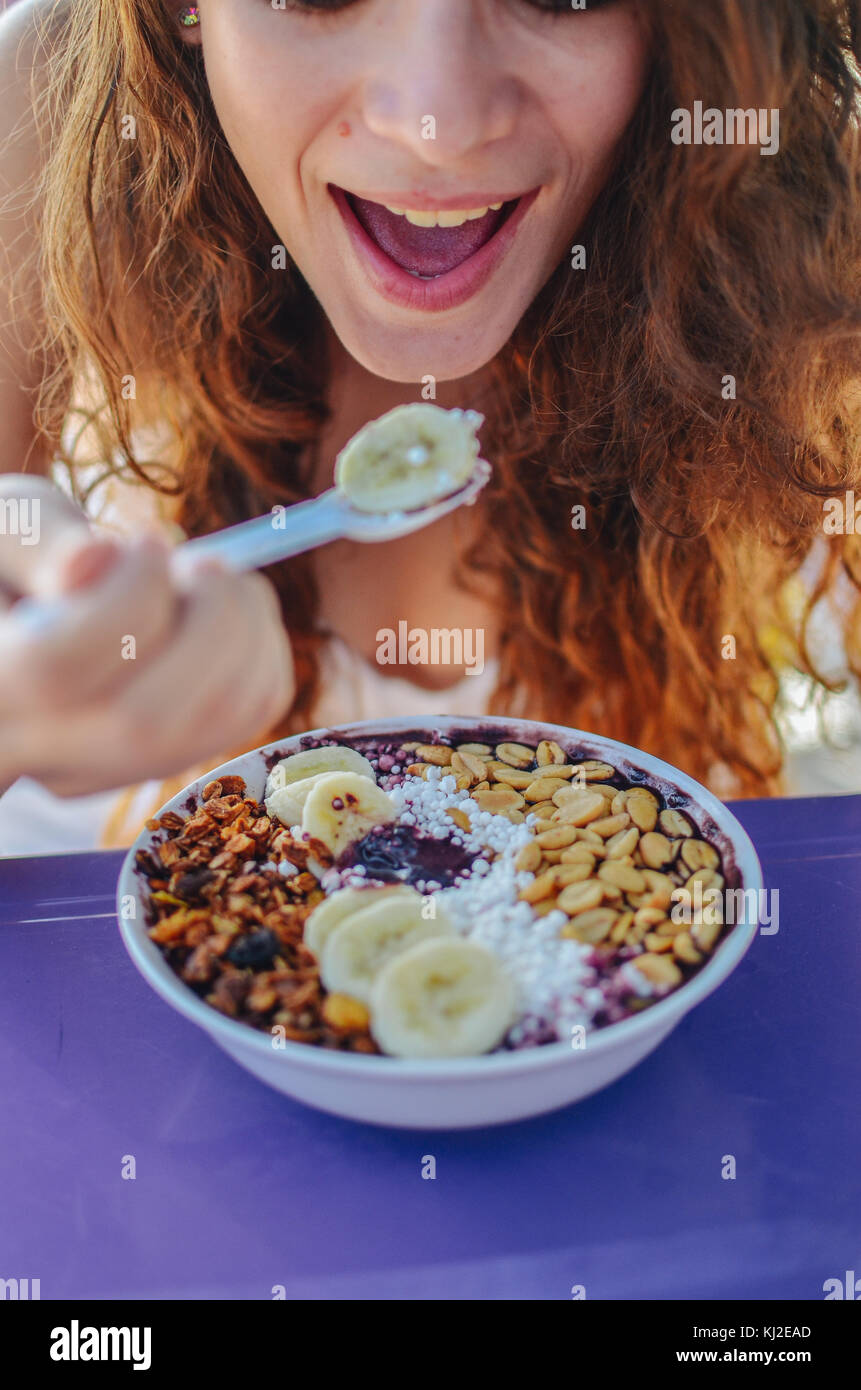 Young woman eating a acai in bowl, with banana, nut and tapioca. A ...