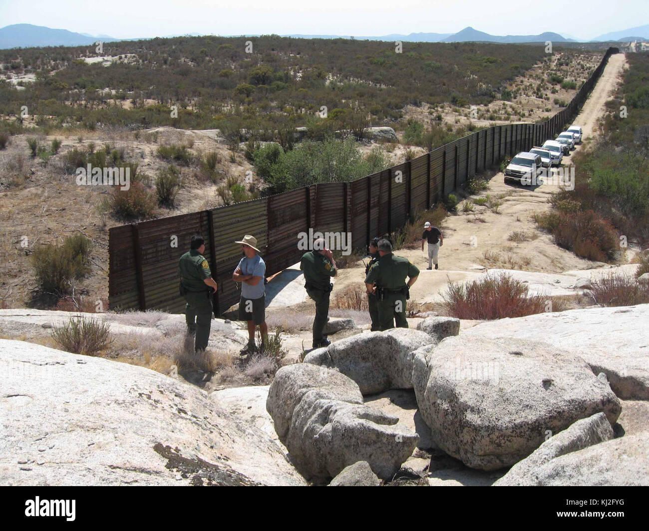 This photograph shows a group of people conversing near a border line ...