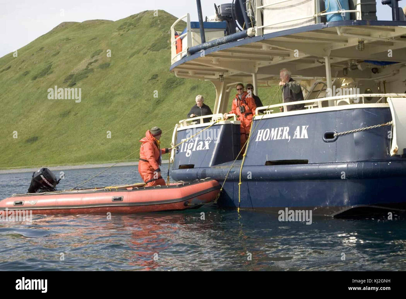 Personel on ship helping person on small boat to dock Stock Photo - Alamy