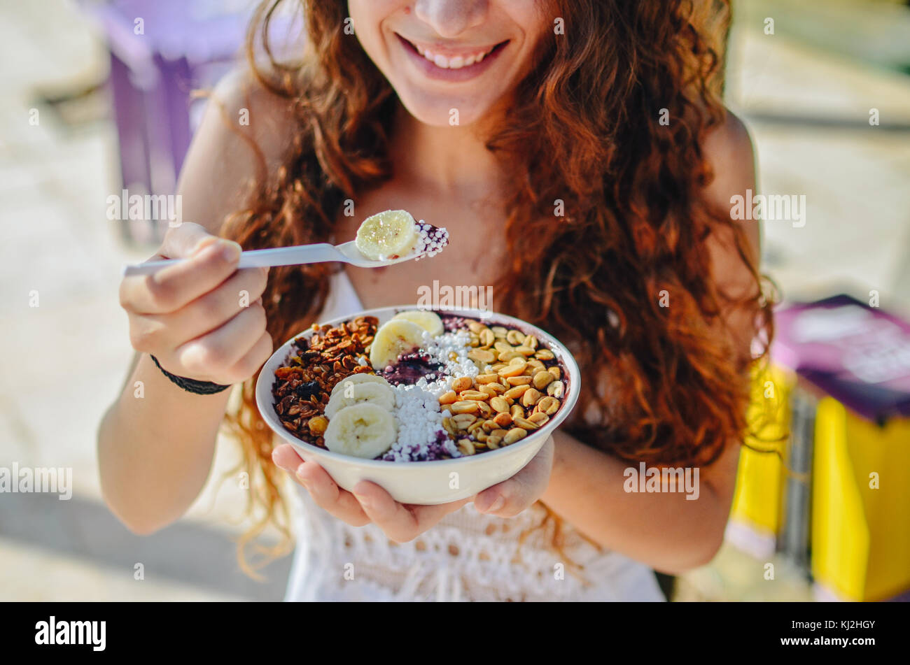 Young woman eating a acai in bowl, with banana, nut and tapioca. A ...