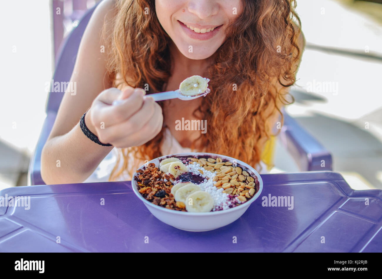 Young woman eating a acai in bowl, with banana, nut and tapioca. A ...