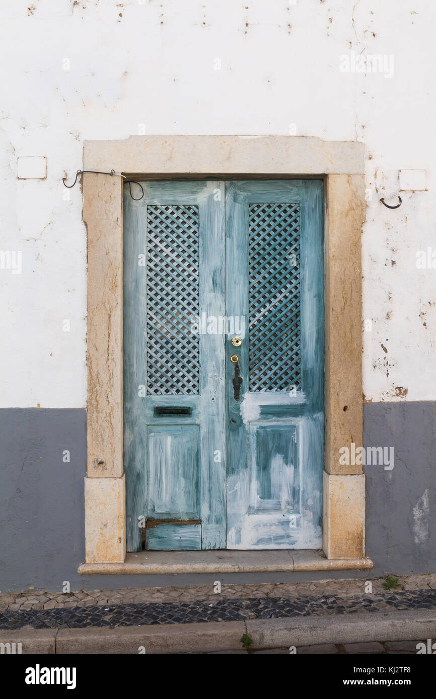 Blue wooden textured gate in a frame made of stone. White wall of the ...