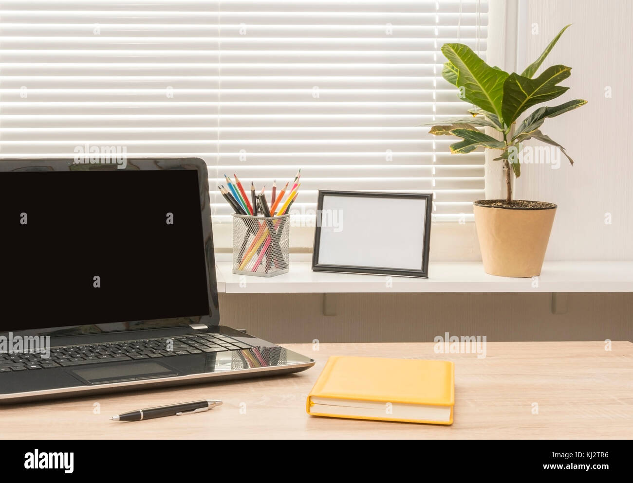 Modern workplace with laptop computer ,yellow note book, pen, photo ...